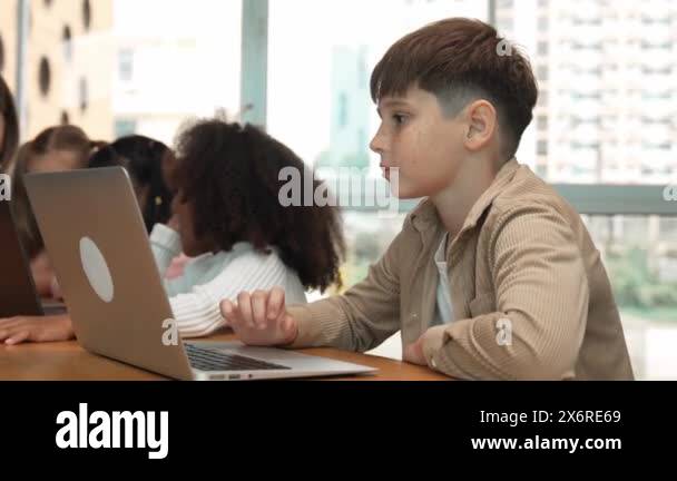 Boy looking at camera with multicultural friend learning prompt at STEM technology class ...