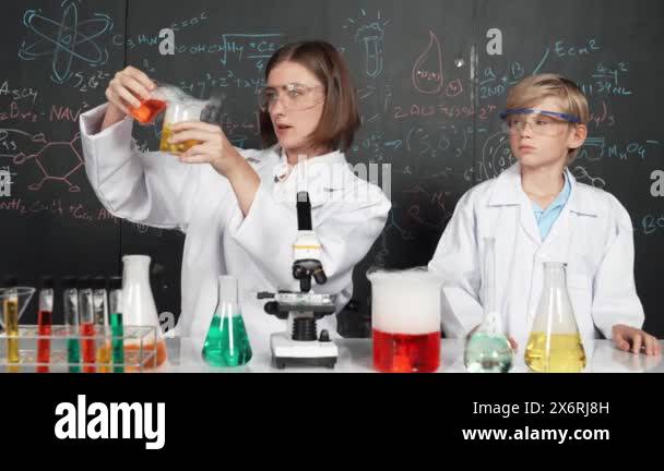 Smart caucasian teacher mixing chemical liquid in science laboratory ...