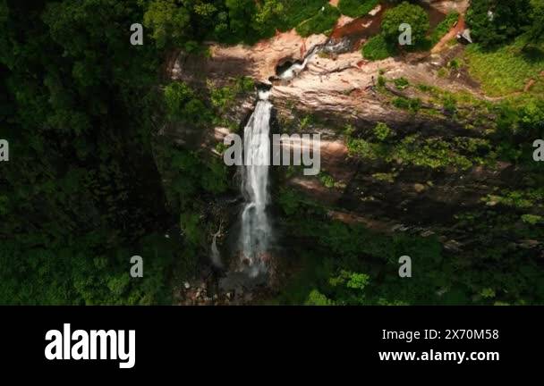 Aerial drone waterfall journey from mountain top to base amid green ...