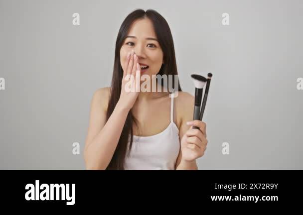 Shocked and scared young chinese woman holds makeup brush, mouth agape ...