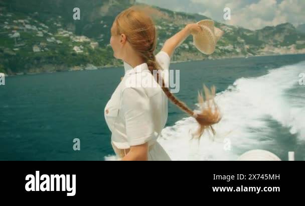 Graceful lady with wind-tossed hair enjoys the sea breeze on a boat ...