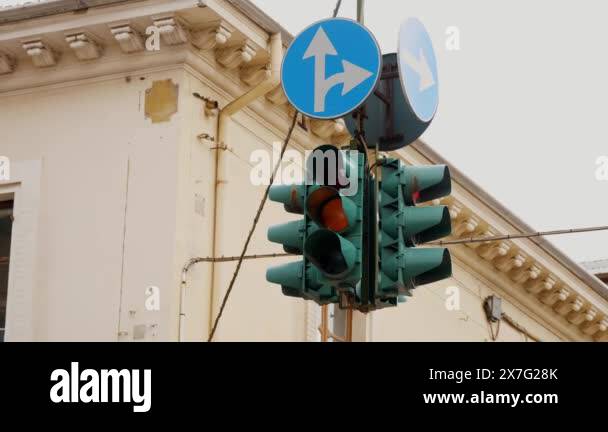 A street-level view of a traffic light featuring green arrows pointing ...
