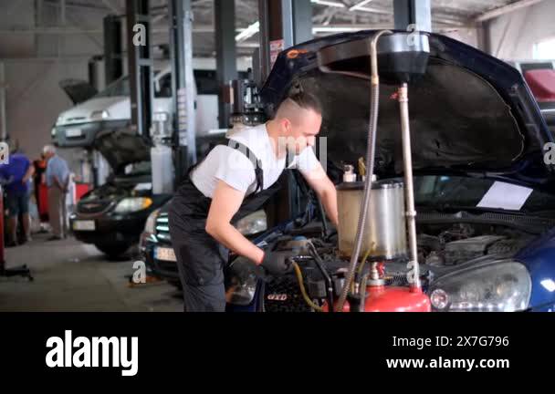 An auto mechanic is working under the hood of a motor vehicle in a ...