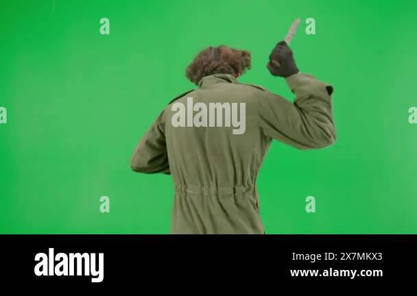 Maniac in jumpsuit running and waving a large sharp knife. An ...