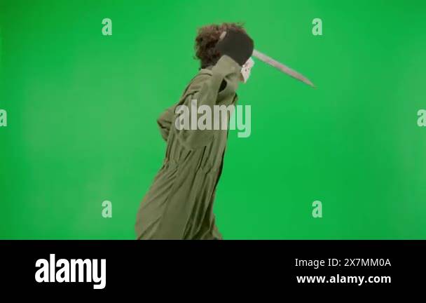 Maniac in hockey mask and jumpsuit running and waving a large sharp ...