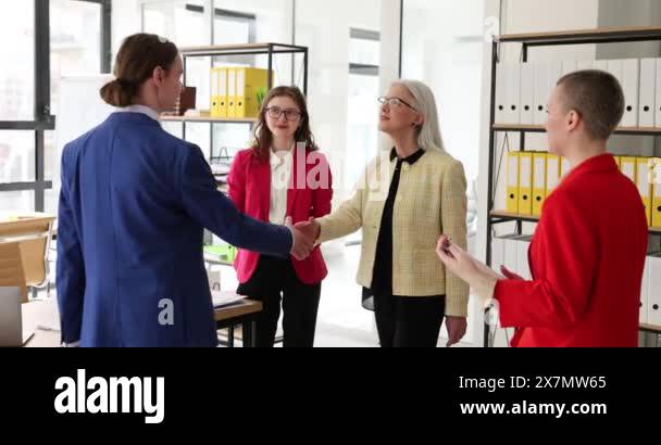 Serious mature boss in glasses shakes hands with young male manager to ...