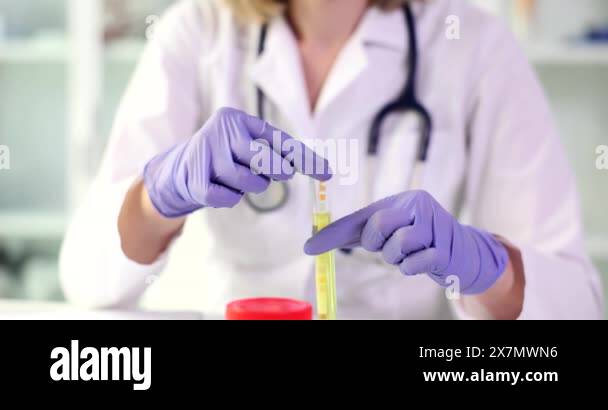 Female chemist in rubber gloves inserts testing stick into tube with ...