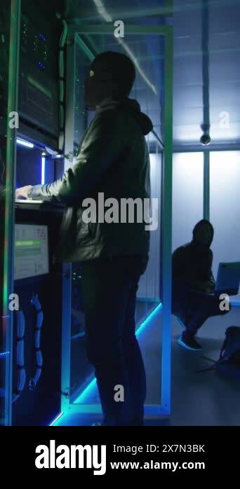 Wide shot of two hackers beginning an attack on servers with laptops in ...