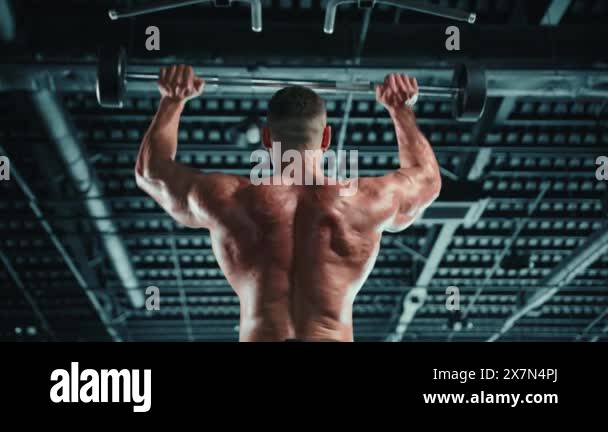 Captured from behind, a dedicated athlete executes an overhead barbell ...