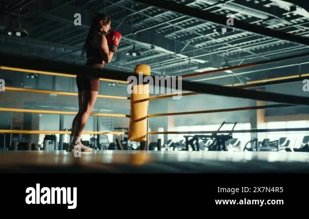 A determined female boxer trains by throwing precise punches in the air ...