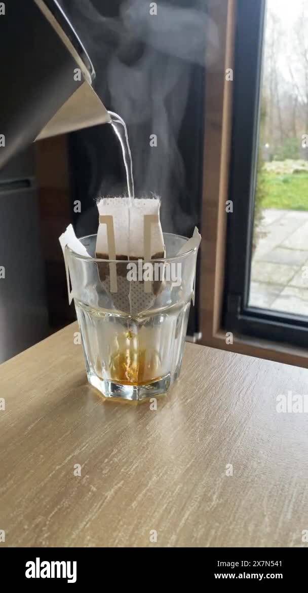 drip coffee brewing woman pours boiling water from a kettle into ...