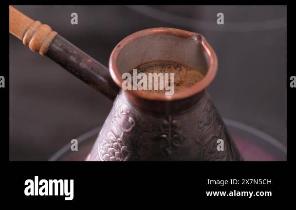 Making Turkish coffee in copper jezve over electric stove. Turk with a ...