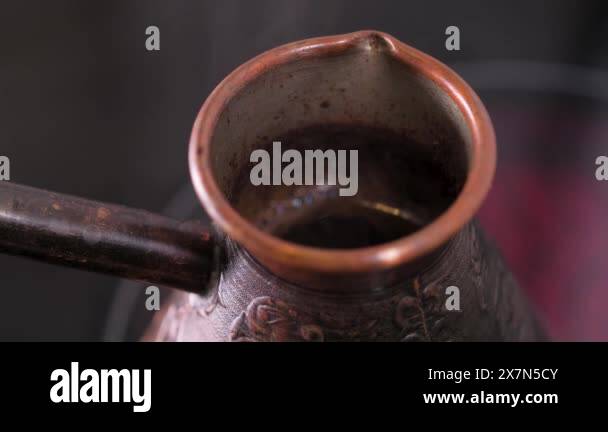 Making Turkish coffee in copper jezve over electric stove. Turk with a ...