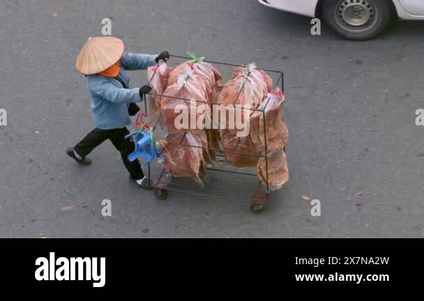 Aerial view of Vietnamese street vendor pulls a cart with food along a ...