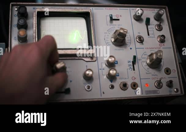 A vintage oscilloscope displays a vibrant green waveform on its screen ...
