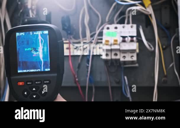 An electrician uses a thermal imager to inspect an electrical panel ...