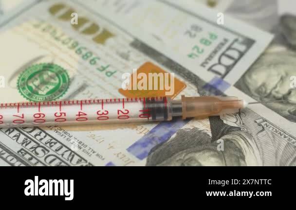 Syringe with new sample of one hundred dollar bills on rotating ...