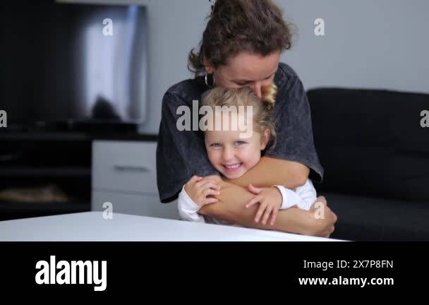 Mom lovingly embracing daughter tightly at home Embracing exude warmth ...