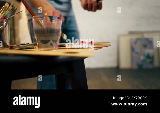 close-up in an art workshop the artist puts paint on the palette with a ...