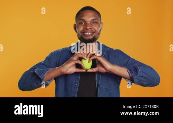 African american relaxed guy does a heart shape sign with an apple ...
