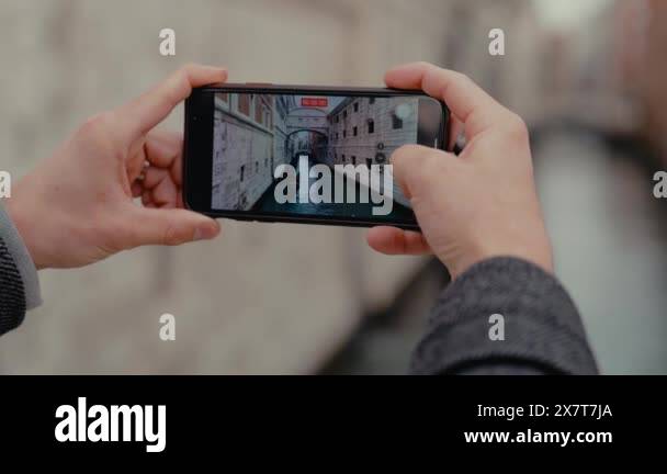 Hands holding a smartphone film the iconic landmarks, gondolas, and ...