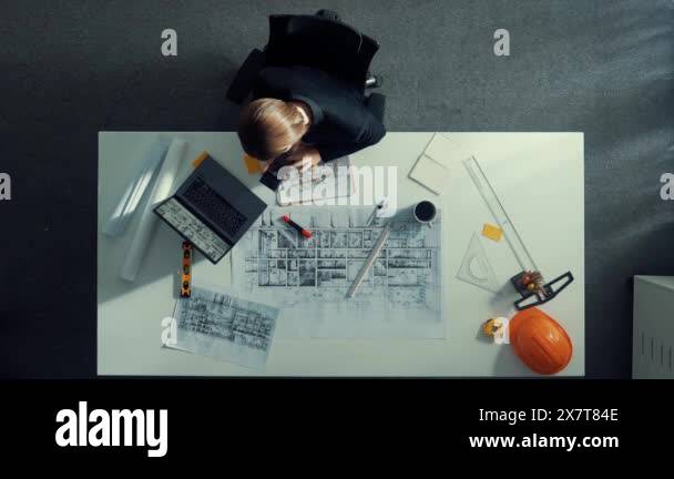 Aerial view of architect drawing while working at laptop. Top down view ...