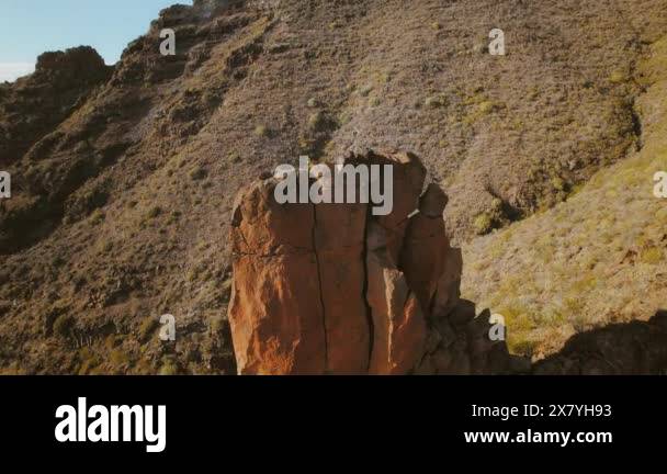 Vertical rock formation amidst a dry, mountainous landscape. Desert ...