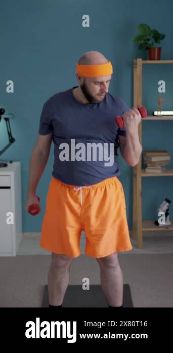 Fat man in shorts and T-shirt does exercises to pump up his biceps ...