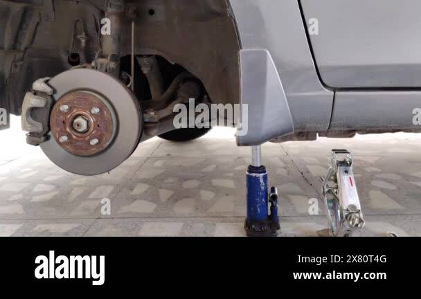 Footage of a car lifted up on a hydraulic jack for changing tyres ...