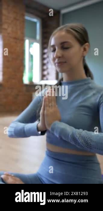 Coach watches people meditating in Lotus pose at yoga class in studio ...