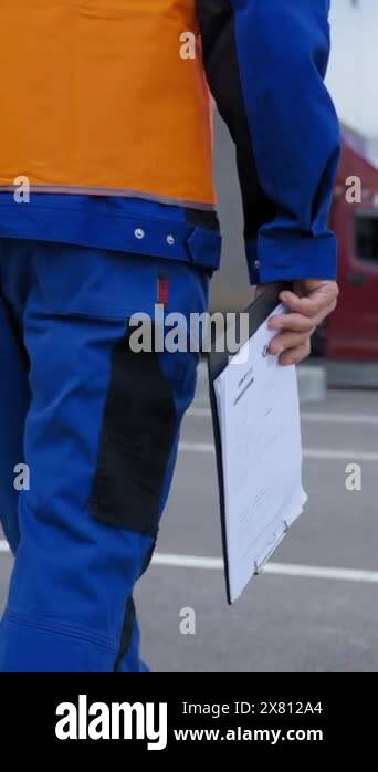 Engineer walks towards truck at terminal gate holding clipboard with ...