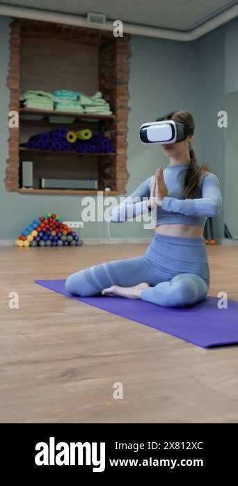 Woman in VR glasses sits in Lotus pose with hands in prayer gesture on ...