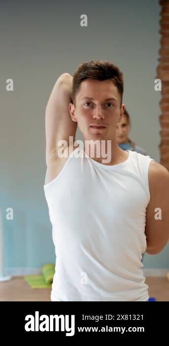 Male coach teaches young women to stretch body at yoga class. Man and ...