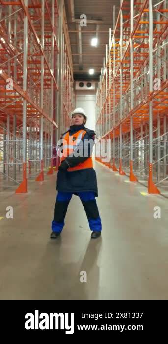 Female engineer dances on aisle between empty metal racks in large ...