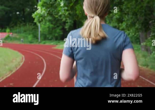 Woman jogging on running track. Female runner training at stadium ...
