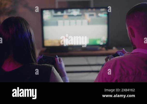 Brother and sister play nostalgic vintage arcade game. Rear shot of two ...