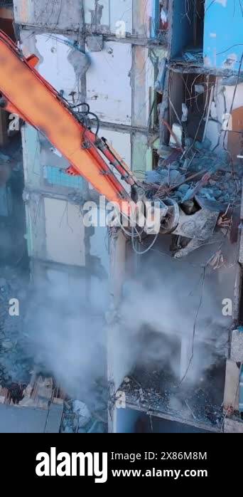 Demolition machine is breaking the floors into pieces and throwing them ...