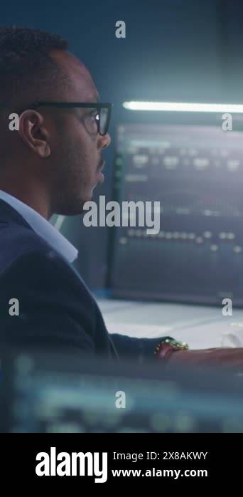 African American software engineer sits in front of computer and big ...