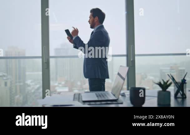 Irritated boss calling smartphone feeling stress at panoramic windows ...