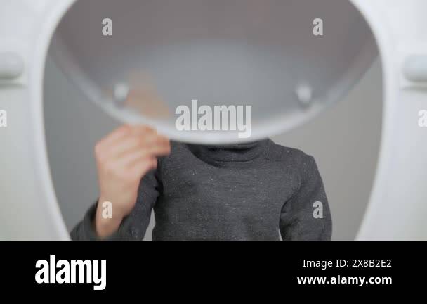 Boy opens toilet lid, looks surprised at bowl, grabs hands to his head ...