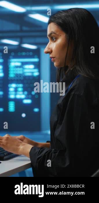 Vertical video Technician working in high tech server room, analyzing ...