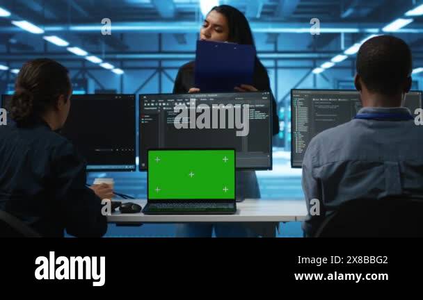 Green screen laptop in data center in front of manager and IT support specialists working ...