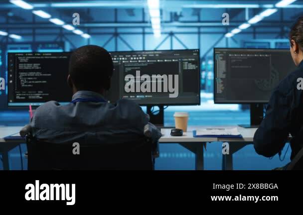 Person with disability next to multiracial coworkers in data center coding on computer ...