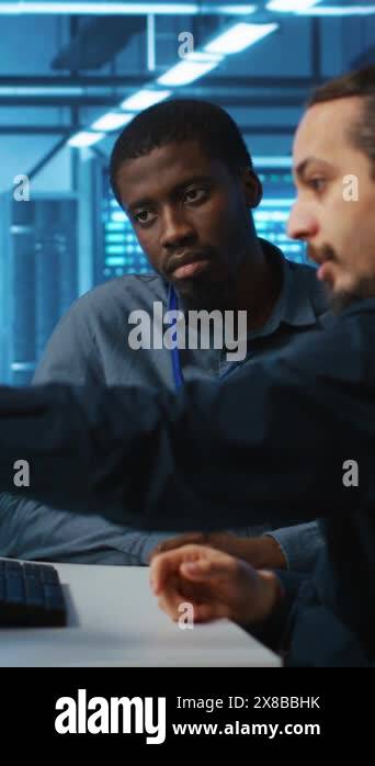 Vertical video Multiracial engineers programming in high tech facility ...