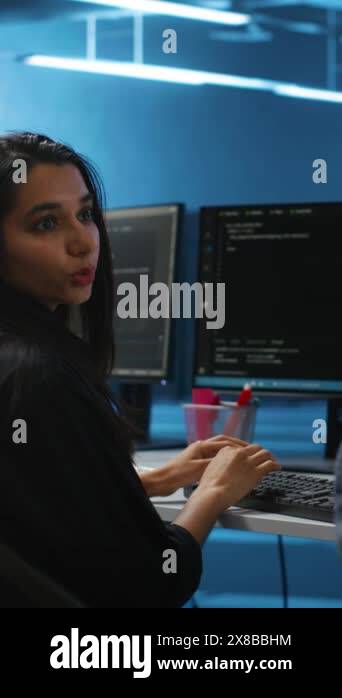 Vertical video Multiethnic team of engineers working in high tech server hub, using PCs to ...