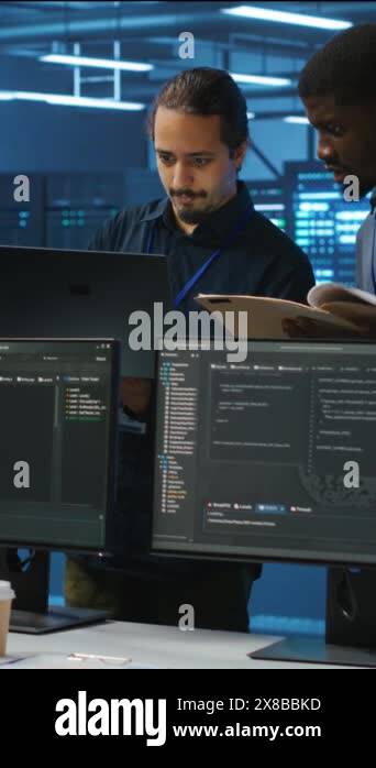 Vertical video Man inspecting server farm, reading paperwork, following inspection checklist ...