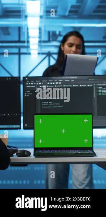 Vertical video Multiethnic engineers working in high tech server hub, using green screen laptop ...