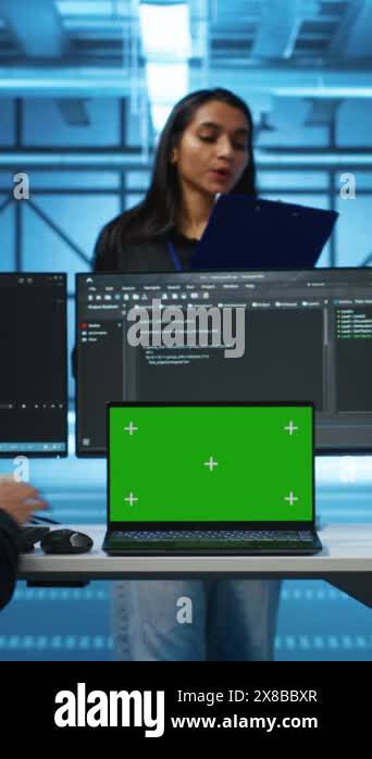 Vertical video Isolated screen laptop in front of IT support workers coding on computers and ...