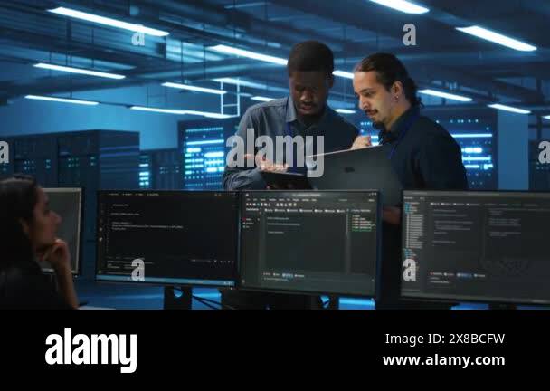 Multiracial team of technicians working in high tech server hub capable of storing vast amounts ...