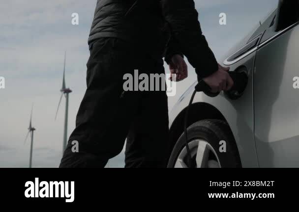 Male hands disconnect power connector from EV car, wind charging ...